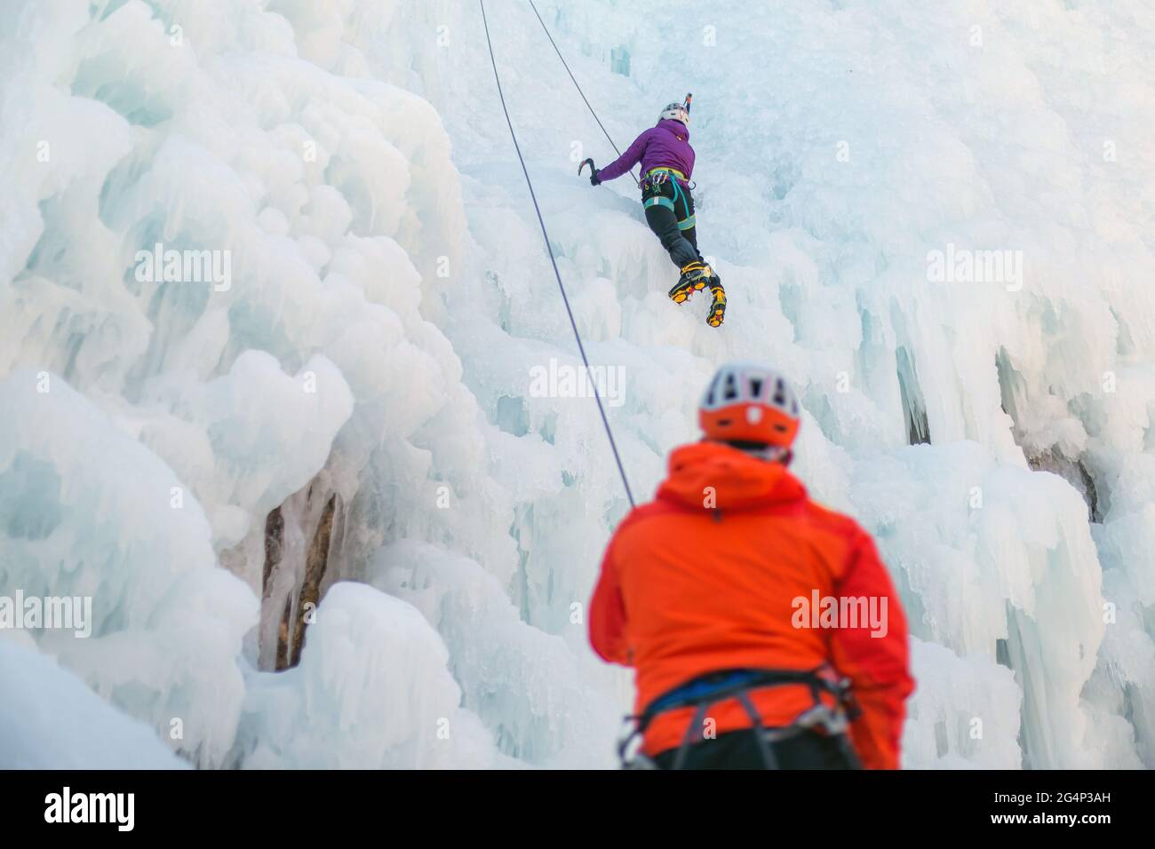 Man standing and controlling a safety top rope while female with ice ...