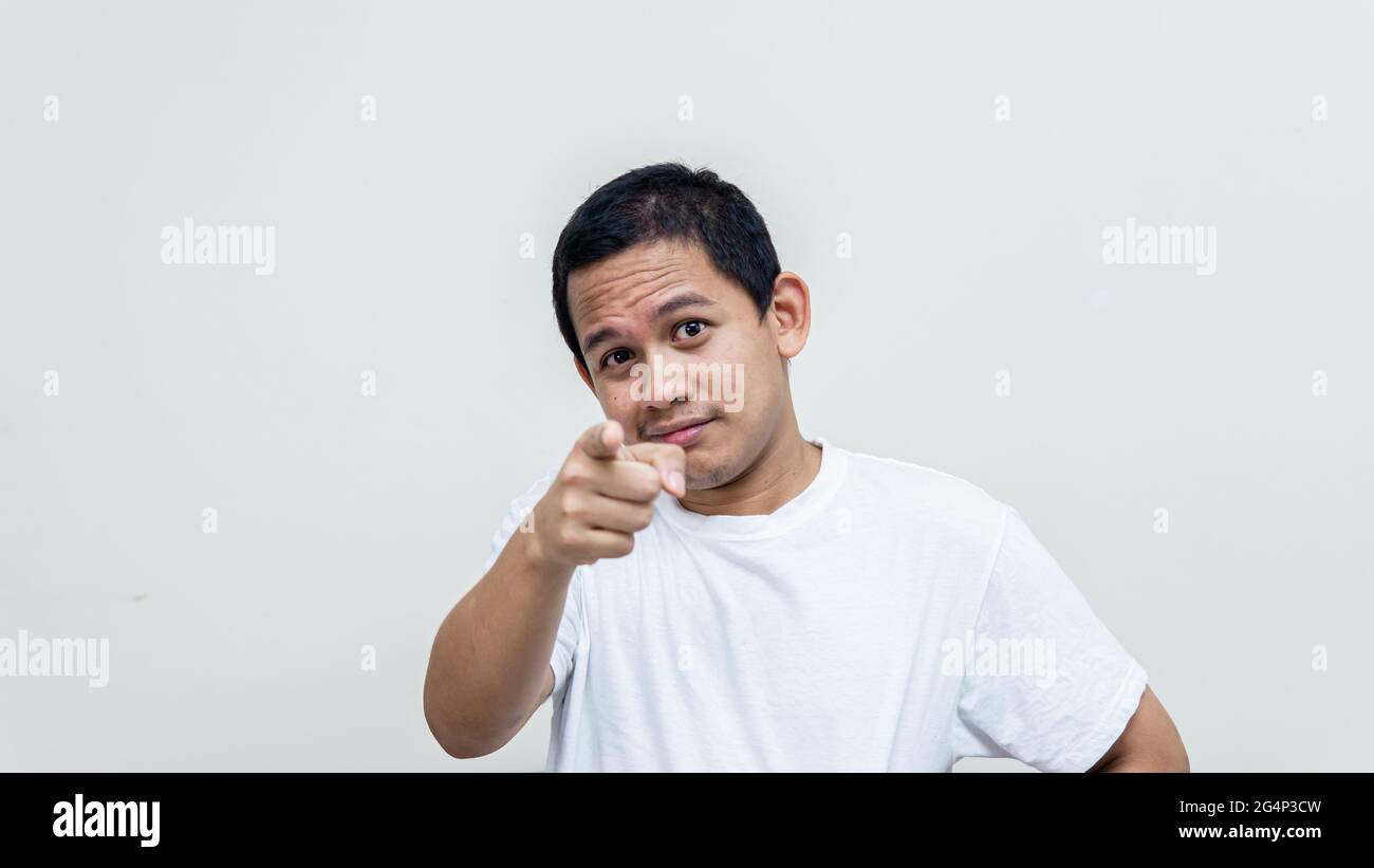 Malay man in a white t-shirt pointing his index finger to the camera on ...