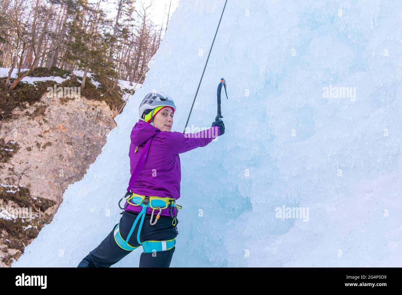 Female ice climber silhouette swinging ice axes on her way up vertical ...