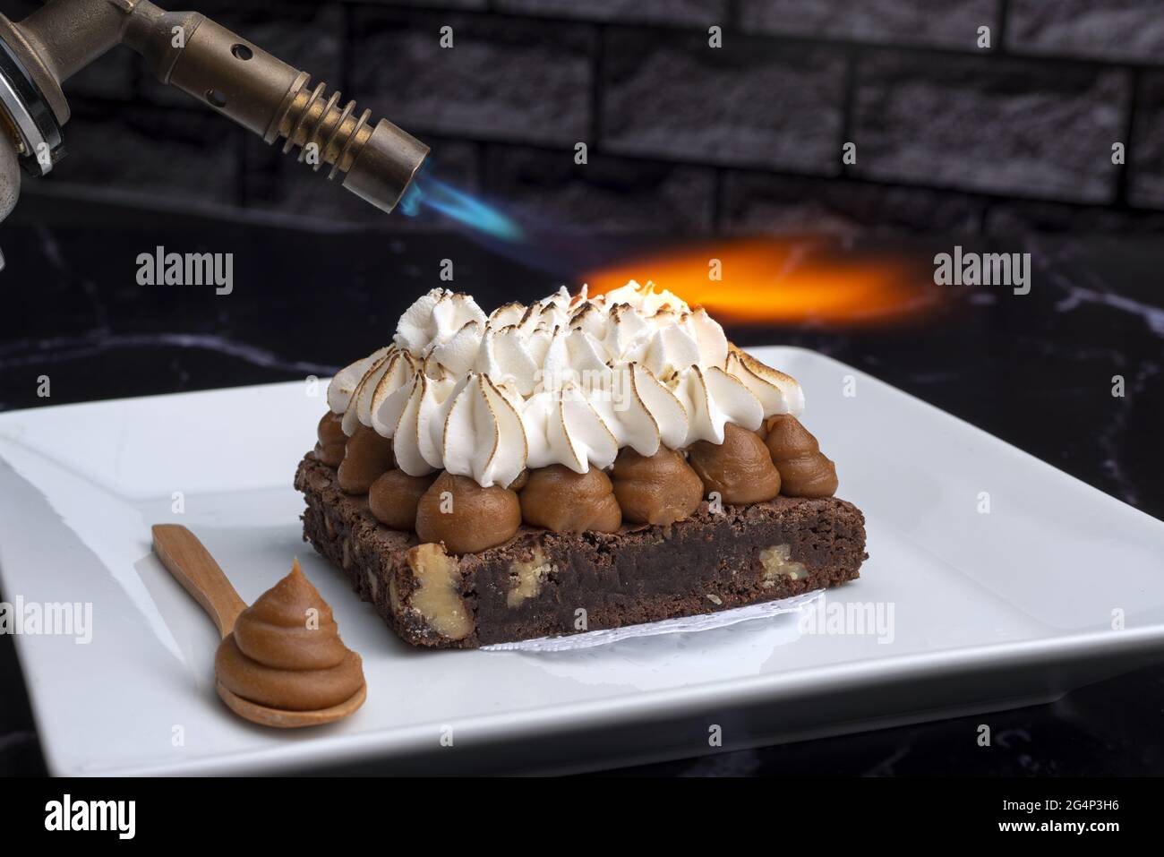 Gas torch burning the cake with chocolate and cream on a large white ...