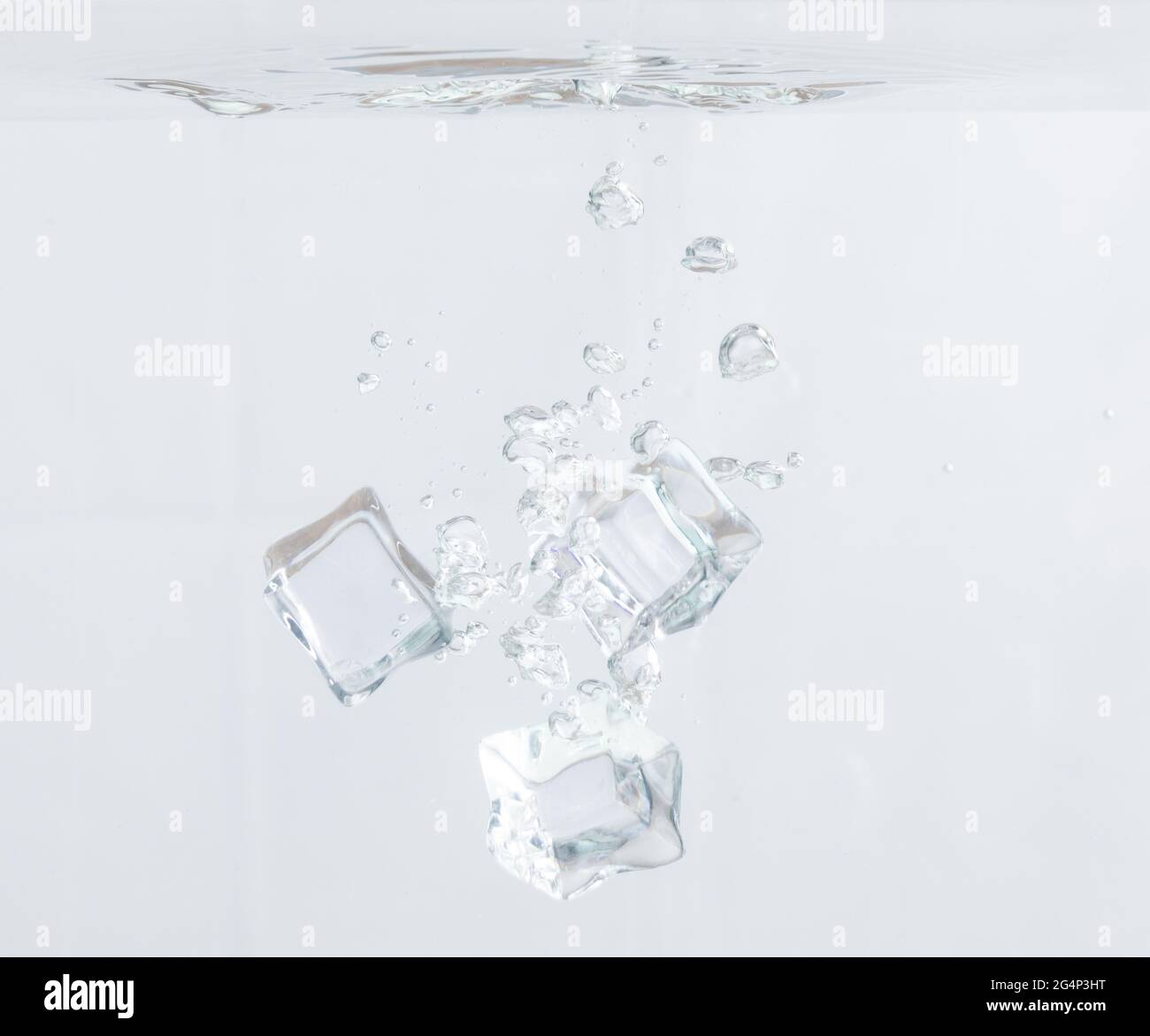 Ice cubes falling into water on white background Stock Photo - Alamy