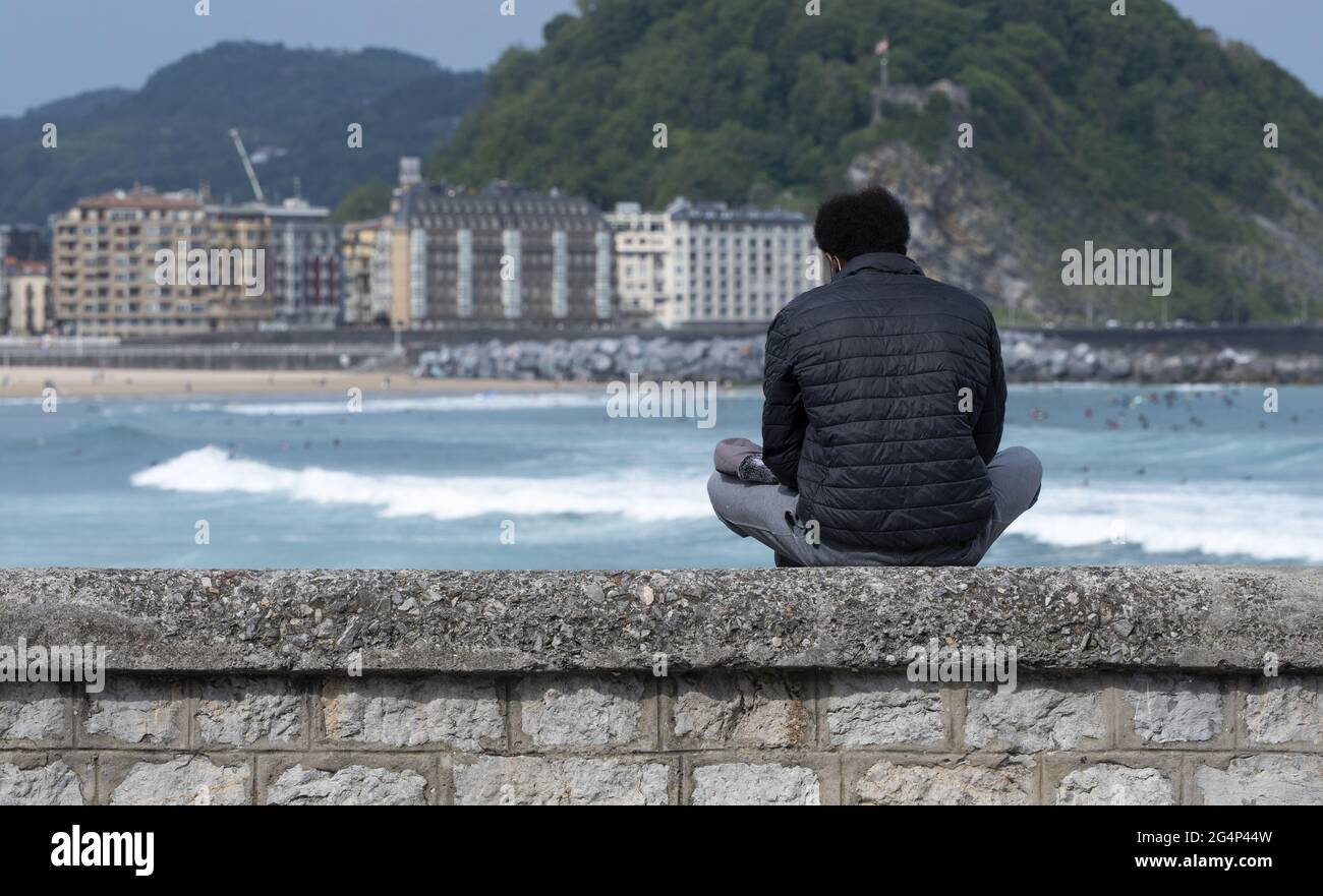 Back view of a man sitting on a harbor and looking at the sea Stock ...