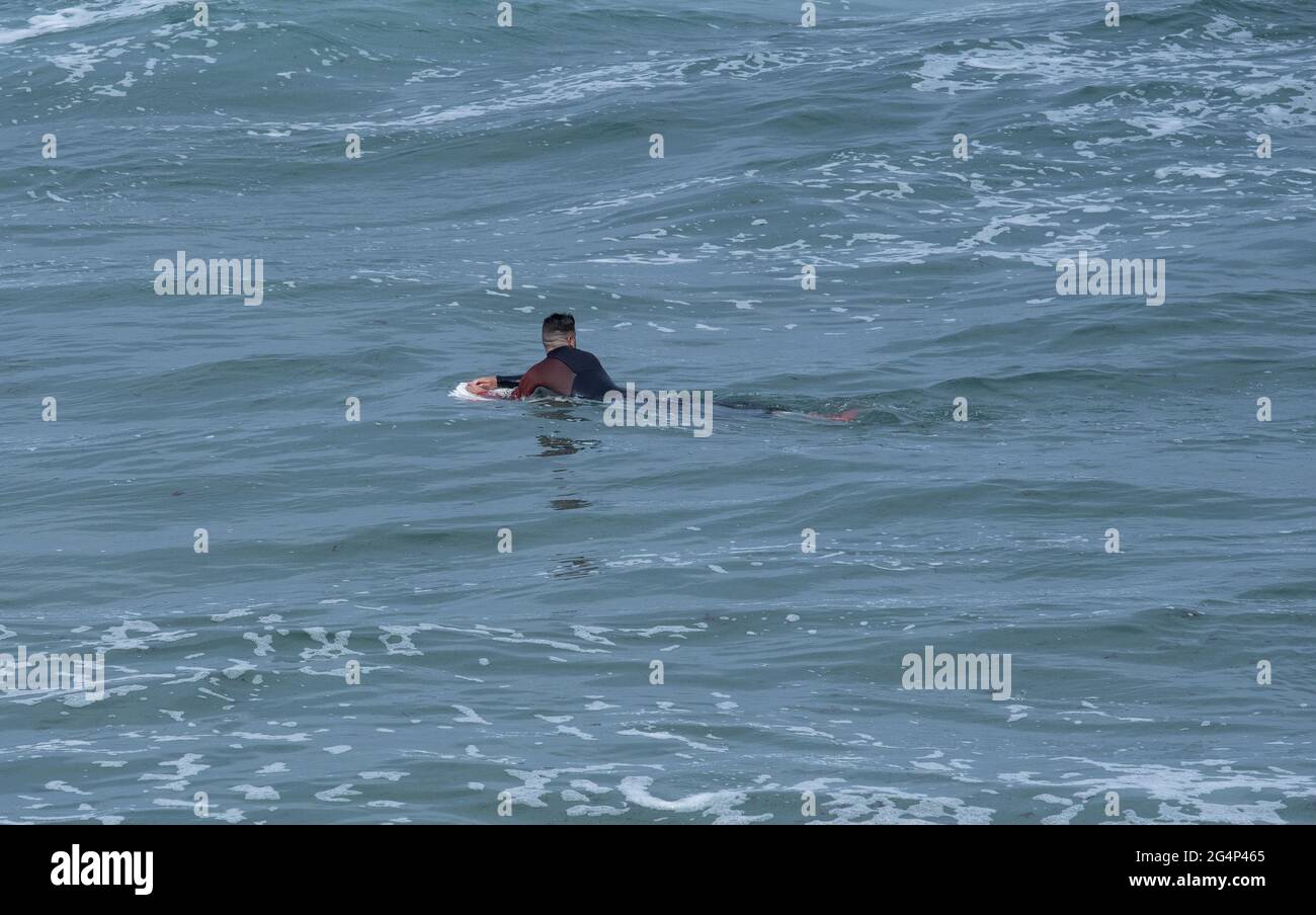 Male surfer lying on his surfboard in the sea Stock Photo - Alamy