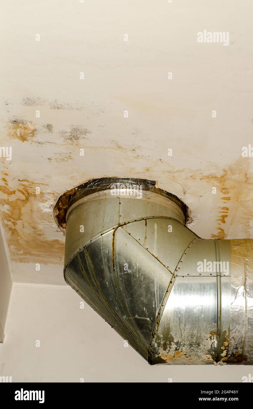 Vertical shot of a rusty metal ventilation duct going into a white ...