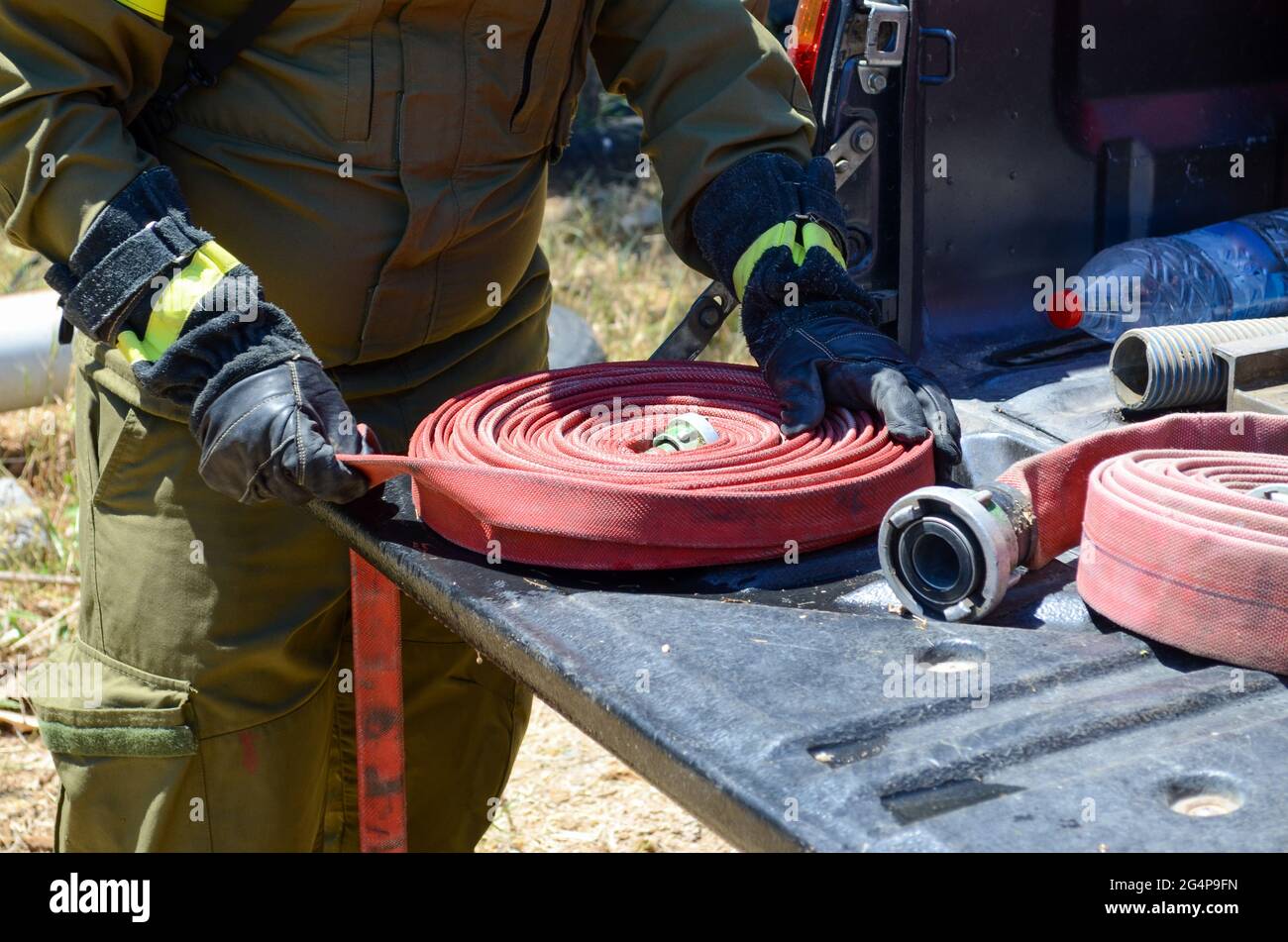 Person in fireman uniform packing a red water hose into a spiral Stock ...