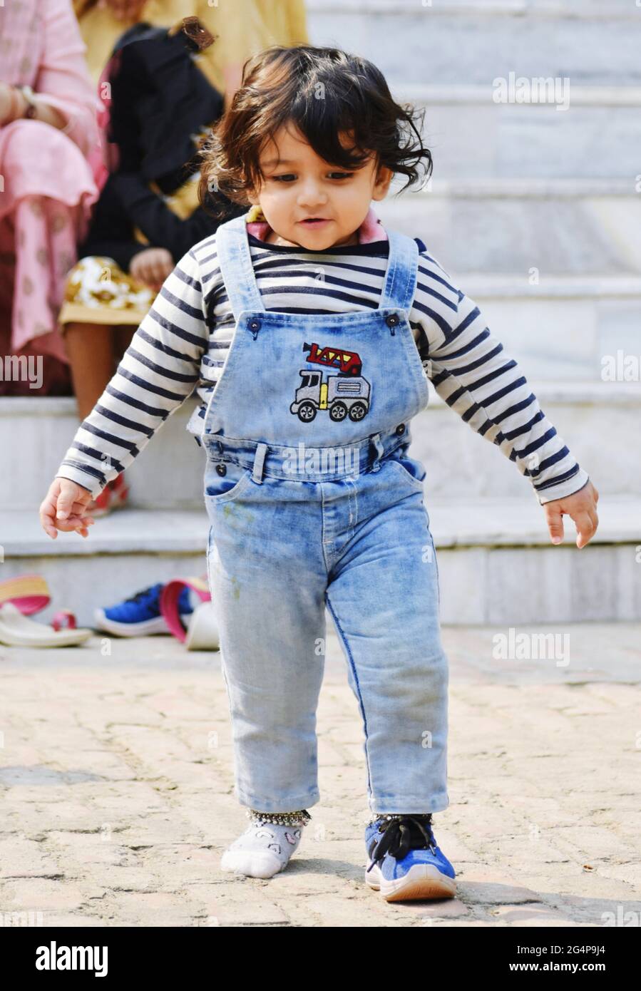 Vertical shot of a cute Indian toddler boy running around with one shoe ...