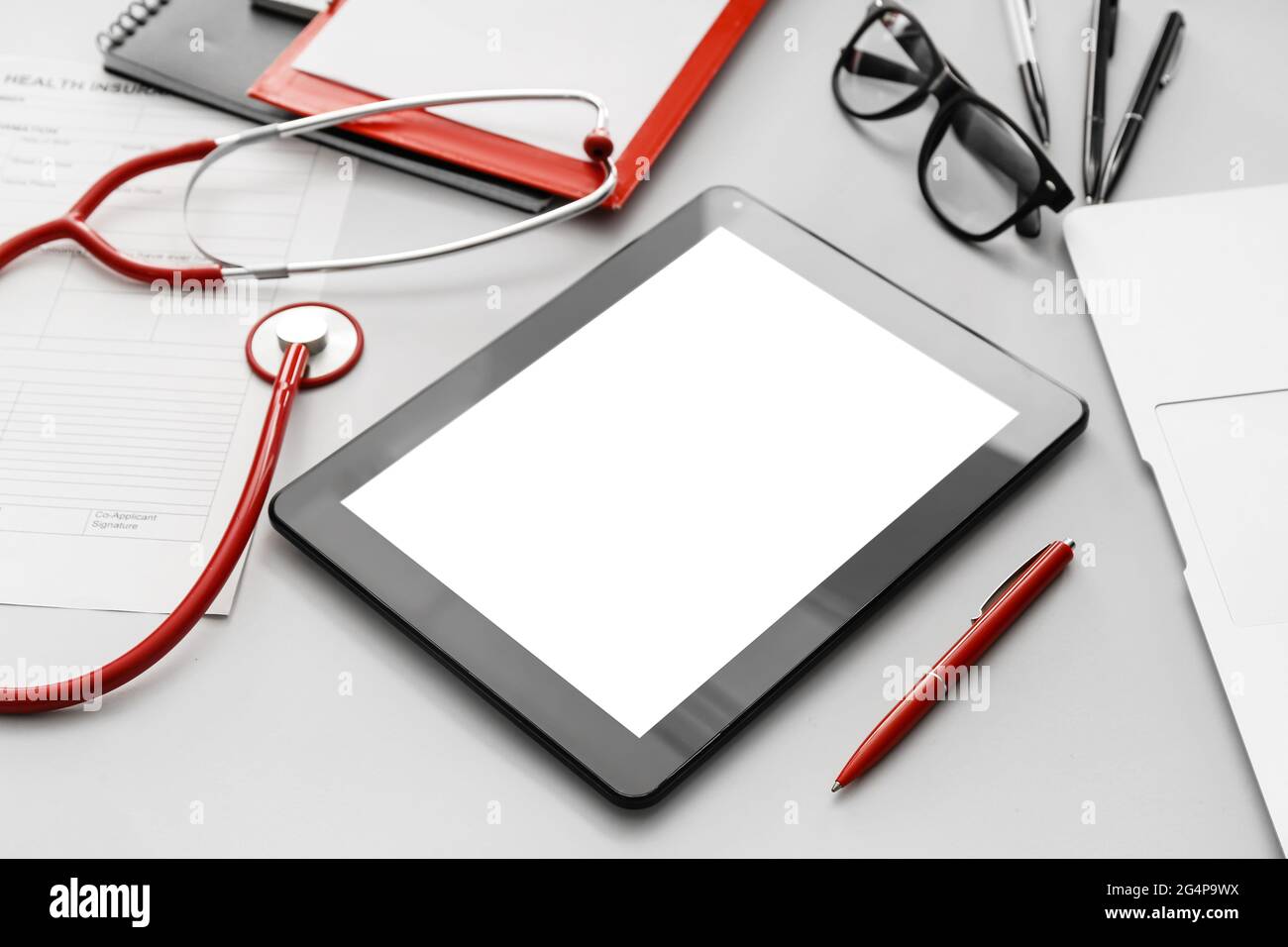 Tablet computer with stethoscope and accessories of doctor on grey ...