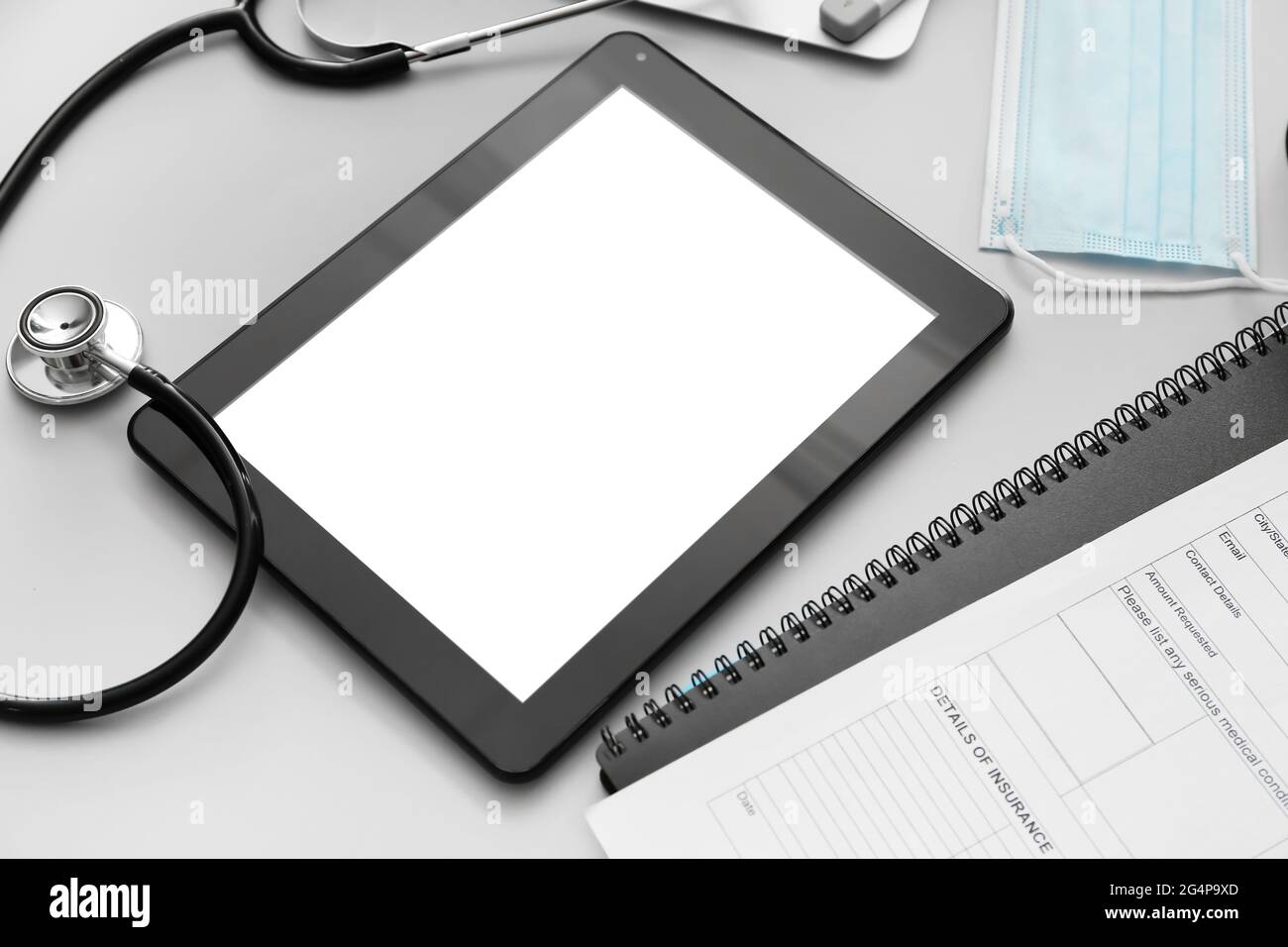 Tablet computer with stethoscope and accessories of doctor on grey ...
