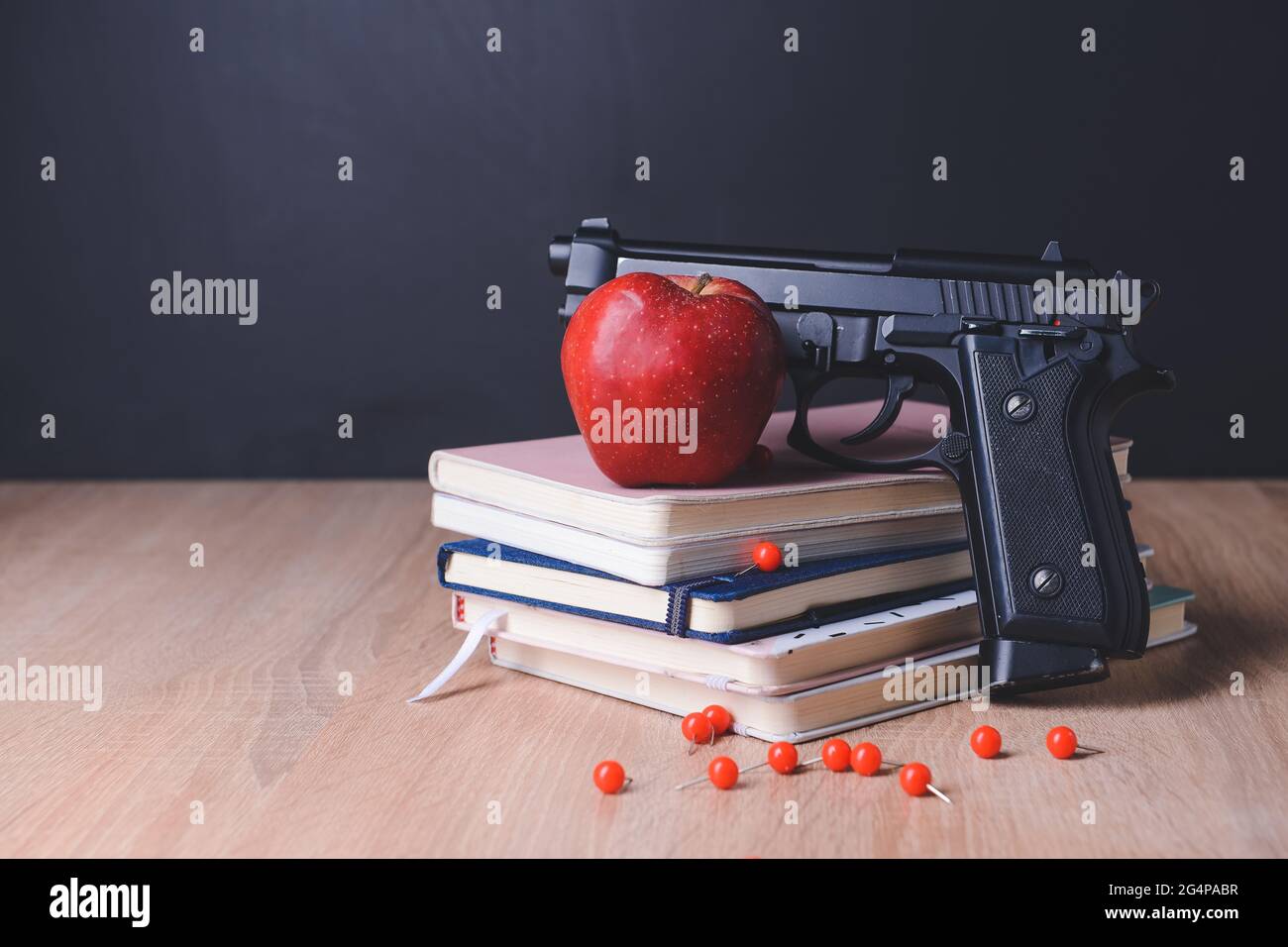 Pistol and apple with books on table in classroom. Concept of school ...