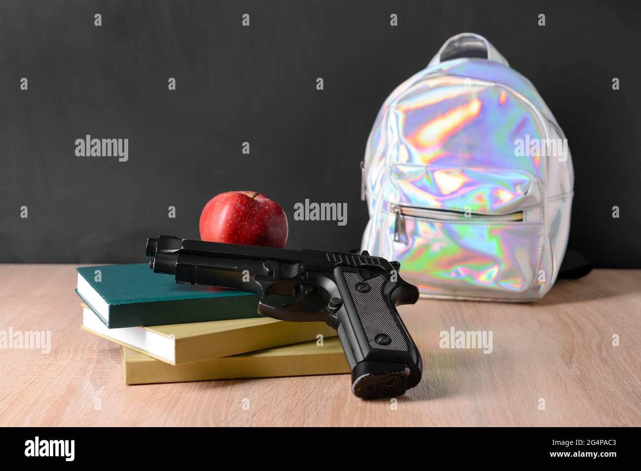 Pistol with books and backpack on table in classroom. Concept of school ...