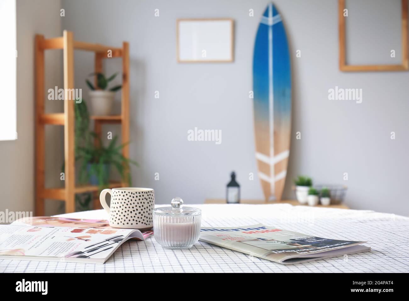 Cup with magazines and aroma candle on dining table Stock Photo - Alamy
