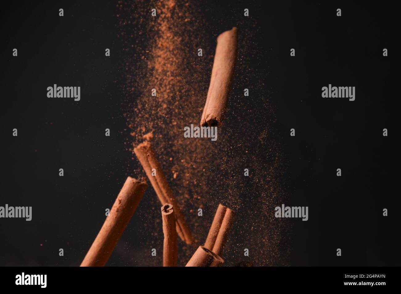 Falling cinnamon sticks and powder on dark background Stock Photo - Alamy