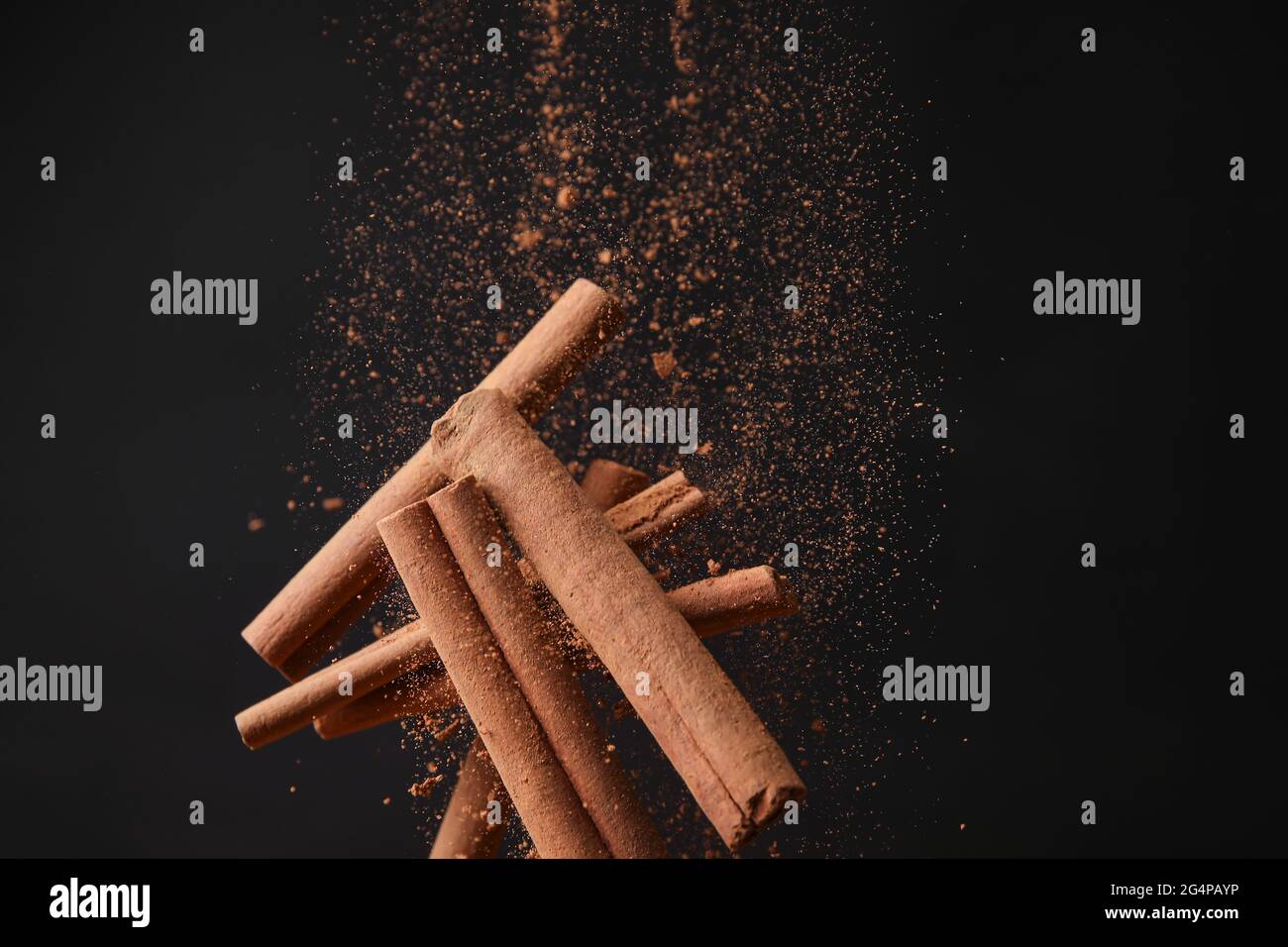Falling cinnamon sticks and powder on dark background Stock Photo - Alamy