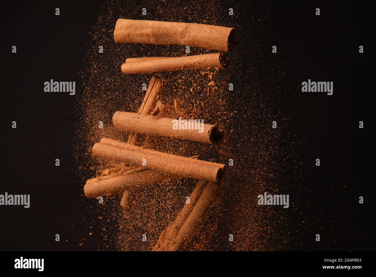 Falling cinnamon sticks and powder on dark background Stock Photo - Alamy