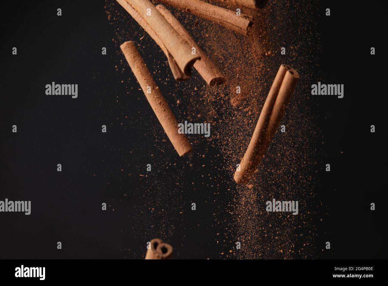 Falling cinnamon sticks and powder on dark background Stock Photo - Alamy