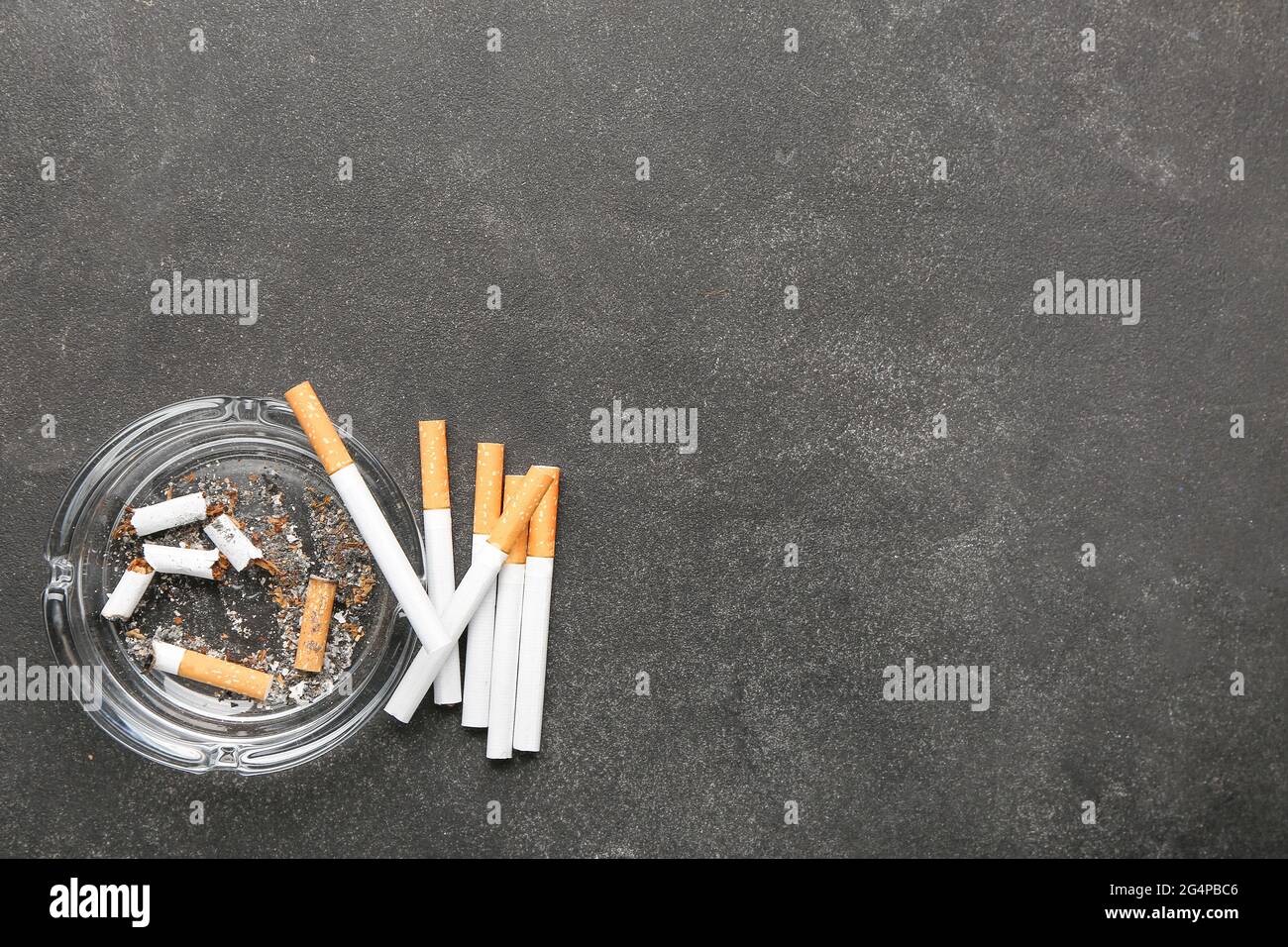 Ash tray with cigarettes on dark background Stock Photo - Alamy