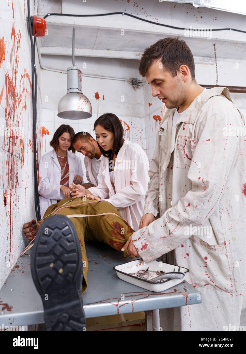 Young adults in escape room with traces of blood Stock Photo - Alamy
