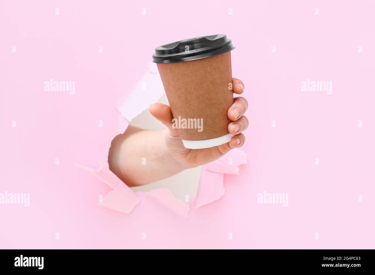 Woman with takeaway cup for coffee visible through hole in torn color ...