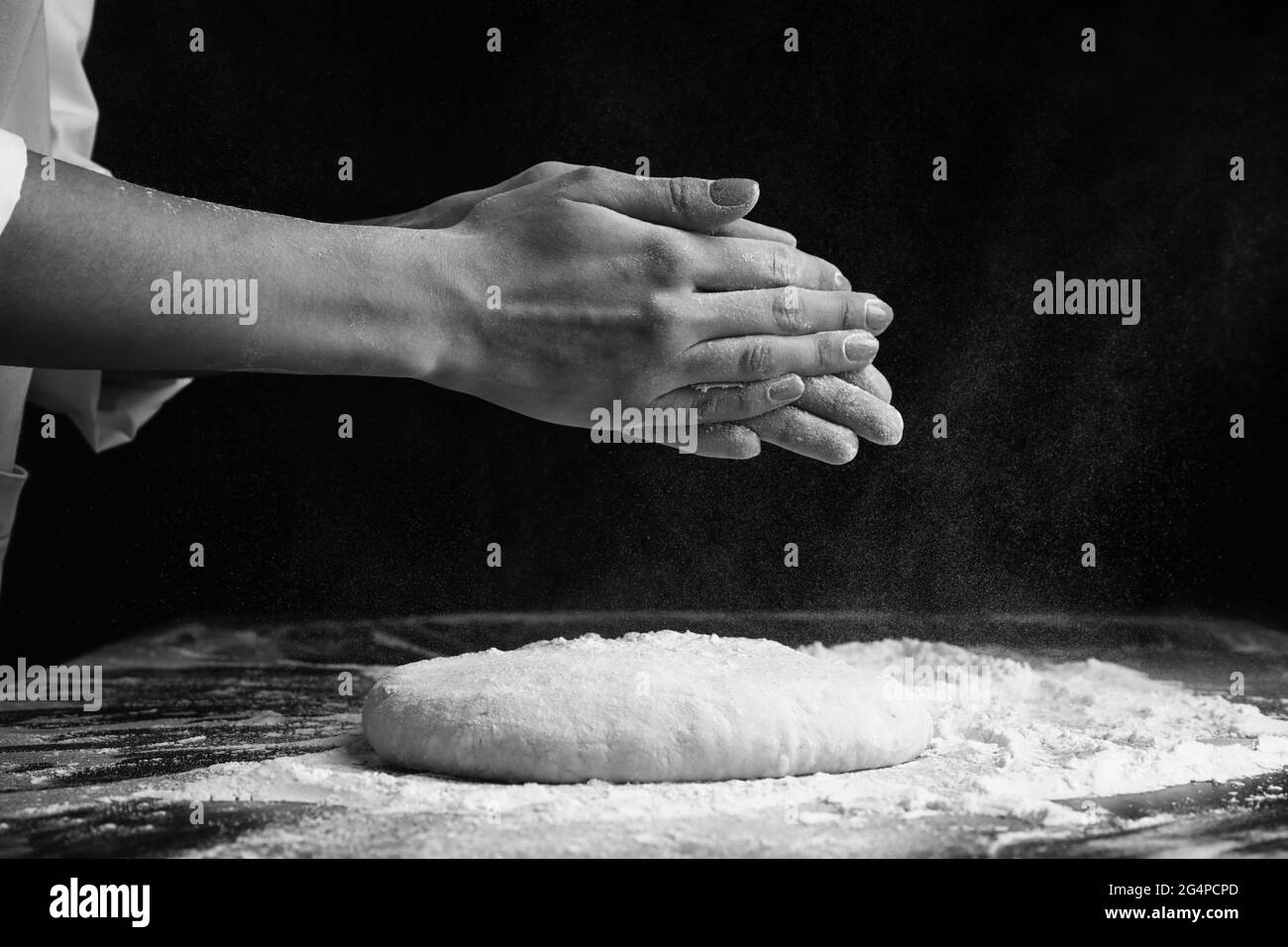 Woman making dough on dark background Stock Photo - Alamy