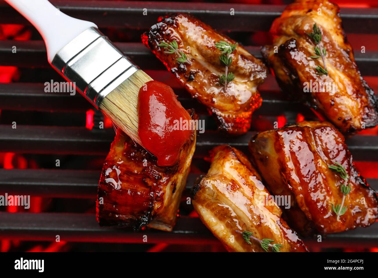 Spreading barbecue sauce on roasted pork on grill Stock Photo - Alamy