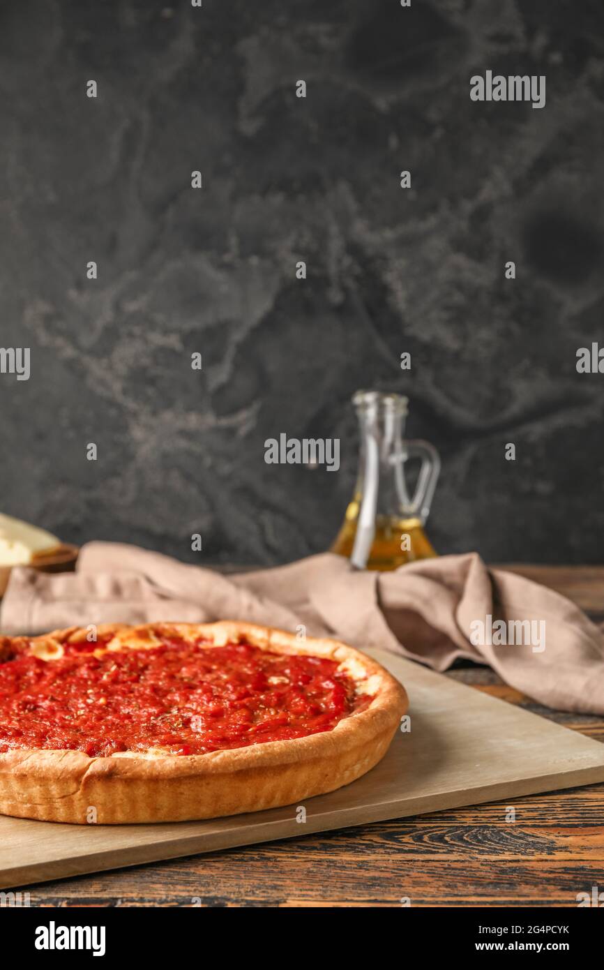 Board with tasty Chicago-style pizza on dark background Stock Photo - Alamy