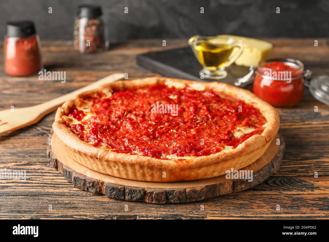 Board with tasty Chicago-style pizza and ingredients on wooden table ...