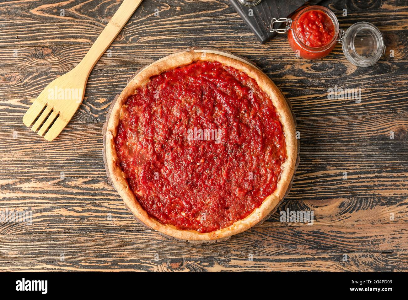 Tasty Chicago-style pizza and sauce on wooden background Stock Photo ...