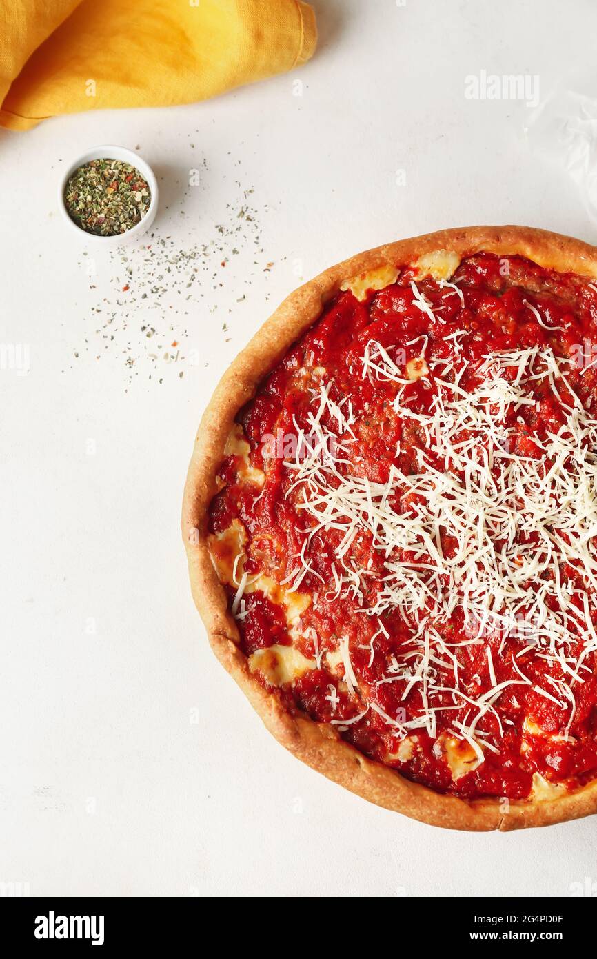 Tasty Chicago-style pizza and spices on light background Stock Photo ...