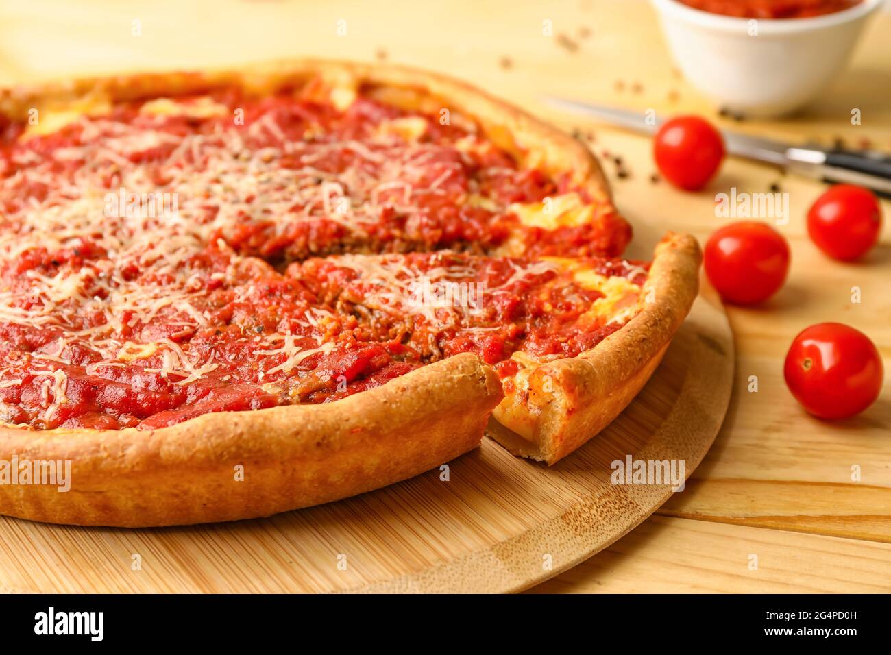 Board with tasty Chicago-style pizza on wooden background, closeup ...
