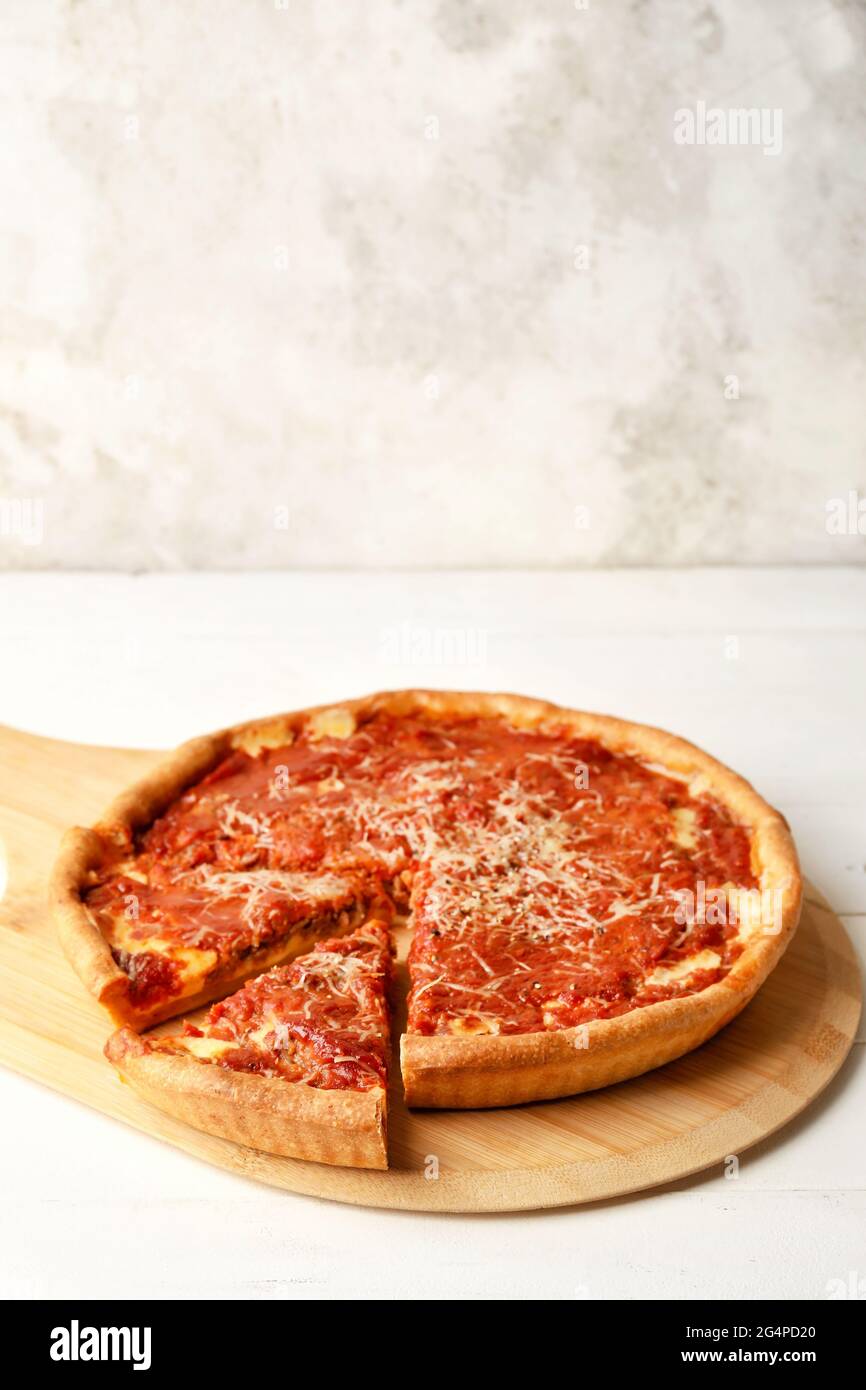 Board with tasty Chicago-style pizza on light background Stock Photo ...