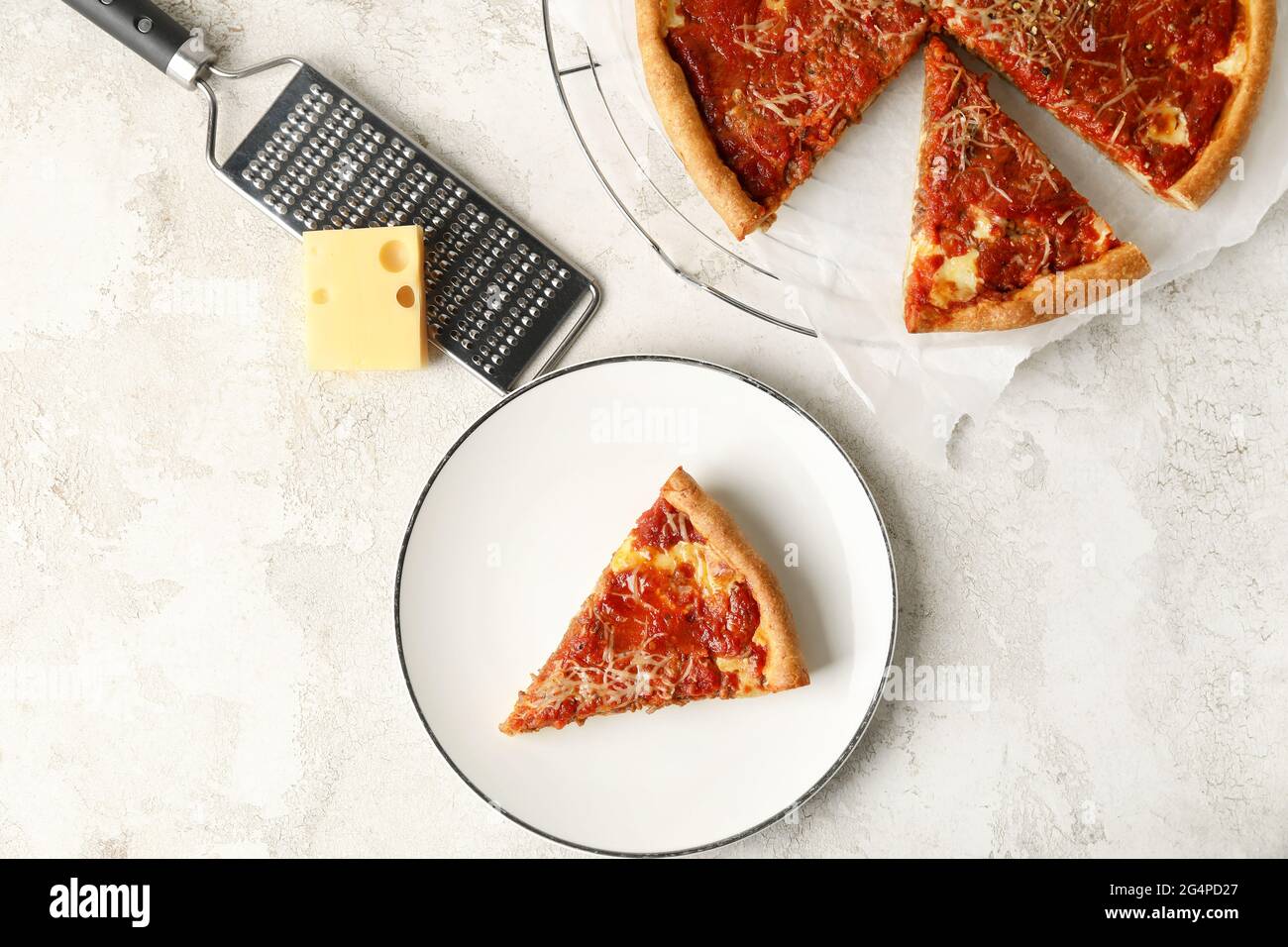 Plate with tasty Chicago-style pizza and cheese on light background ...