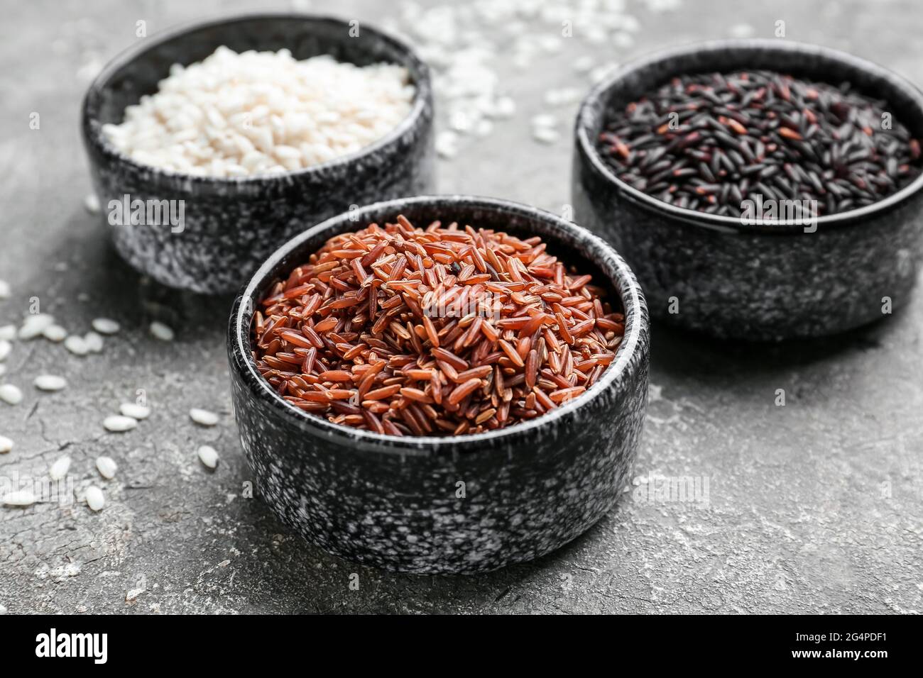Bowls with different types of raw rice on grunge background Stock Photo ...
