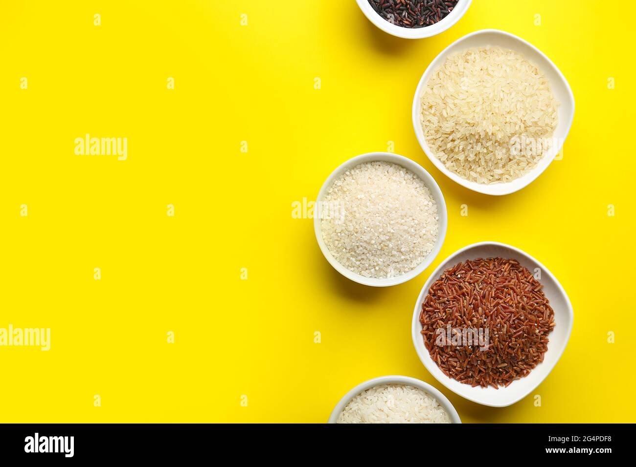 Bowls with different types of raw rice on color background Stock Photo ...