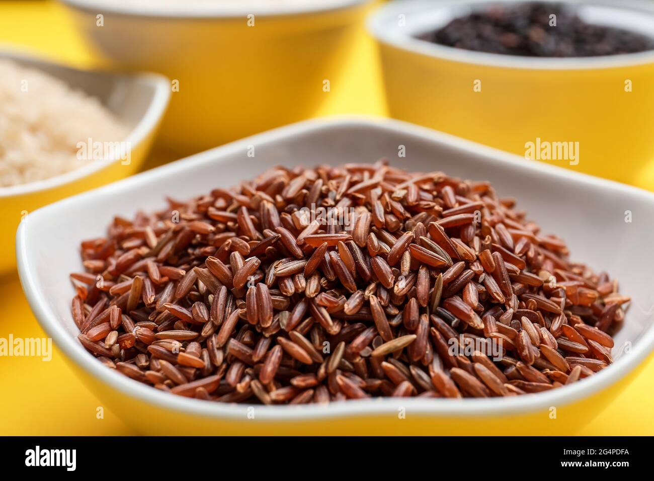 Bowls with different types of raw rice on color background, closeup ...