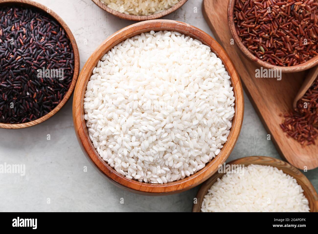 Bowls with different types of raw rice on light background Stock Photo ...