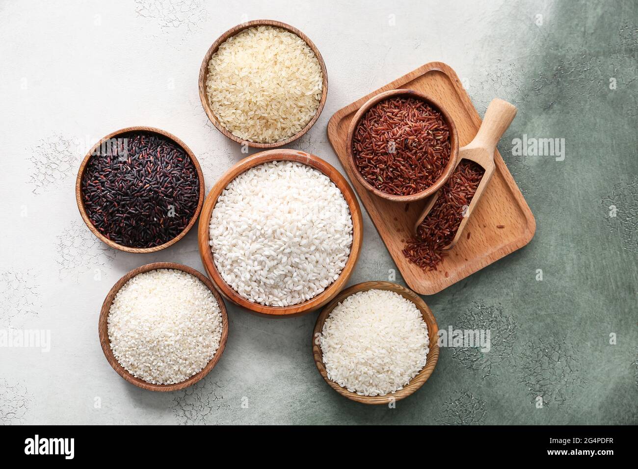 Bowls with different types of raw rice on color background Stock Photo ...