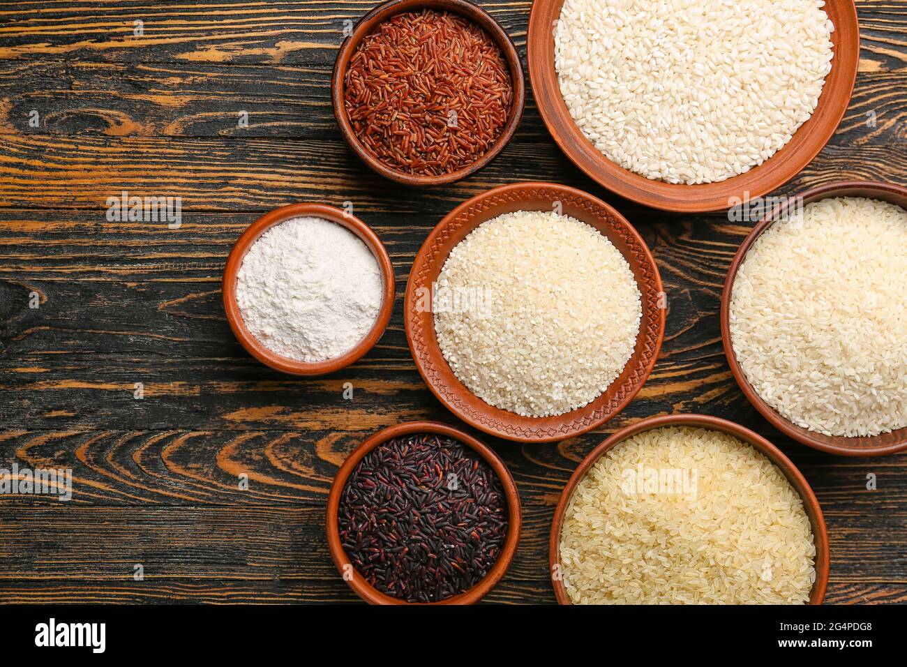Bowls with different types of raw rice on wooden background Stock Photo ...