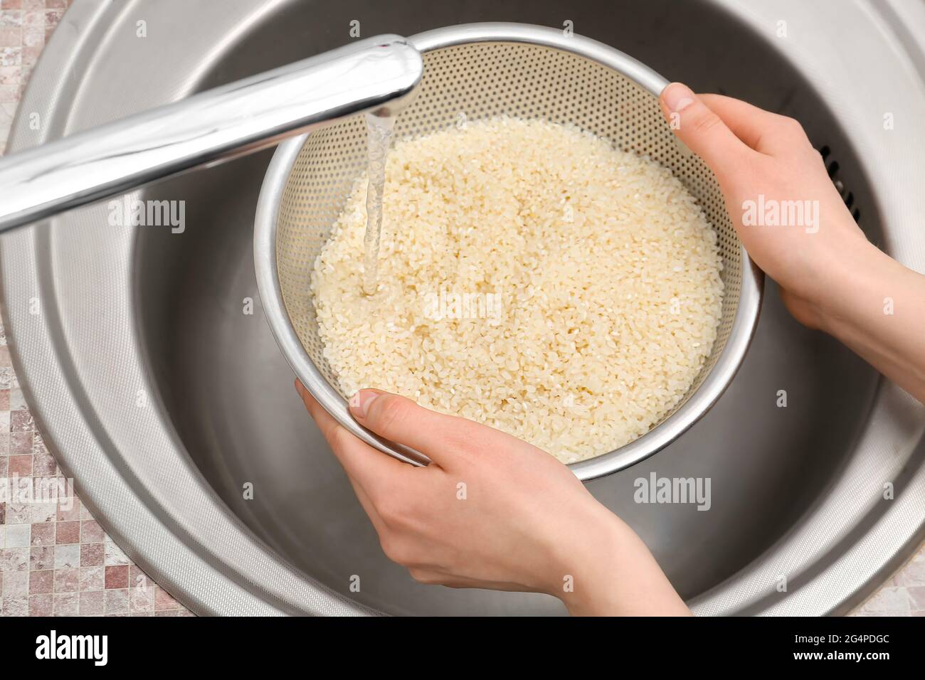 Woman rinsing rice in sifter under running water Stock Photo - Alamy