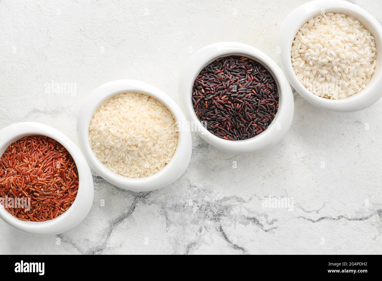 Bowls with different types of raw rice on light background Stock Photo ...
