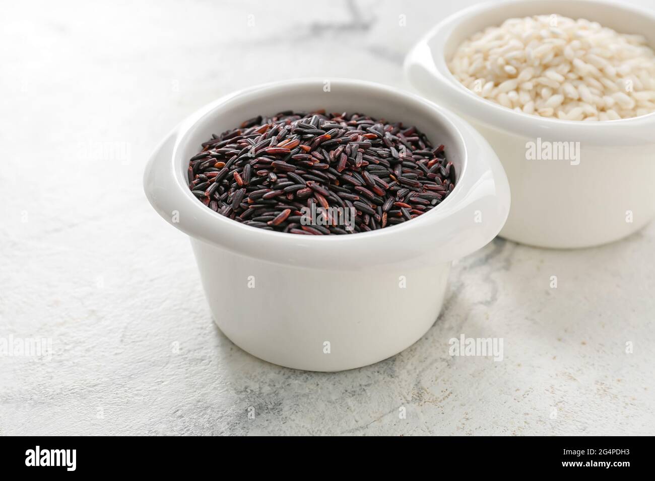 Bowls with different types of raw rice on light background Stock Photo ...