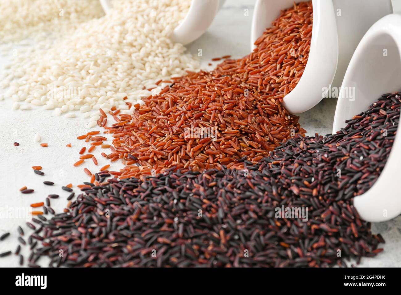 Overturned bowls with different types of raw rice on light background ...