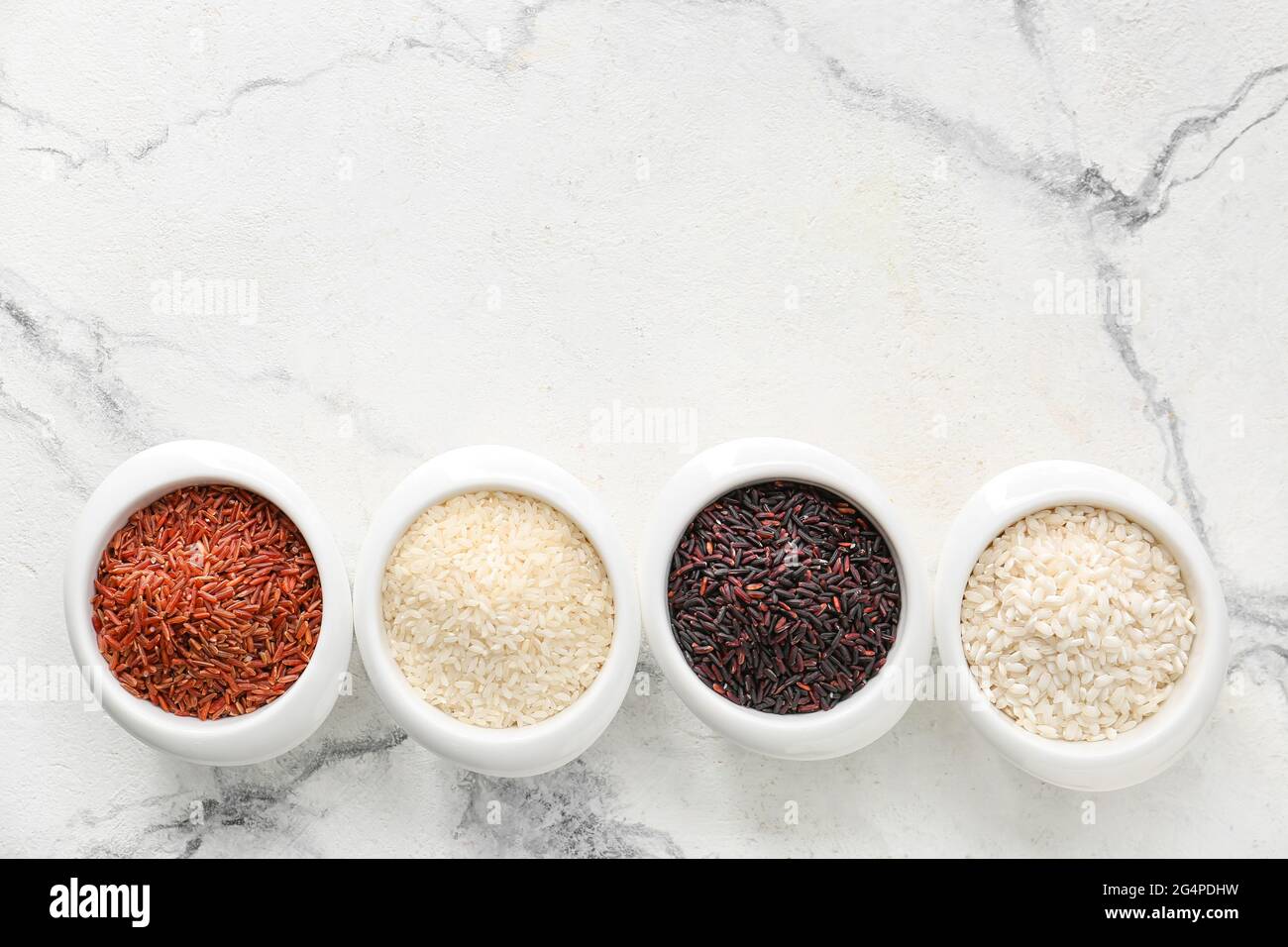 Bowls with different types of raw rice on light background Stock Photo ...