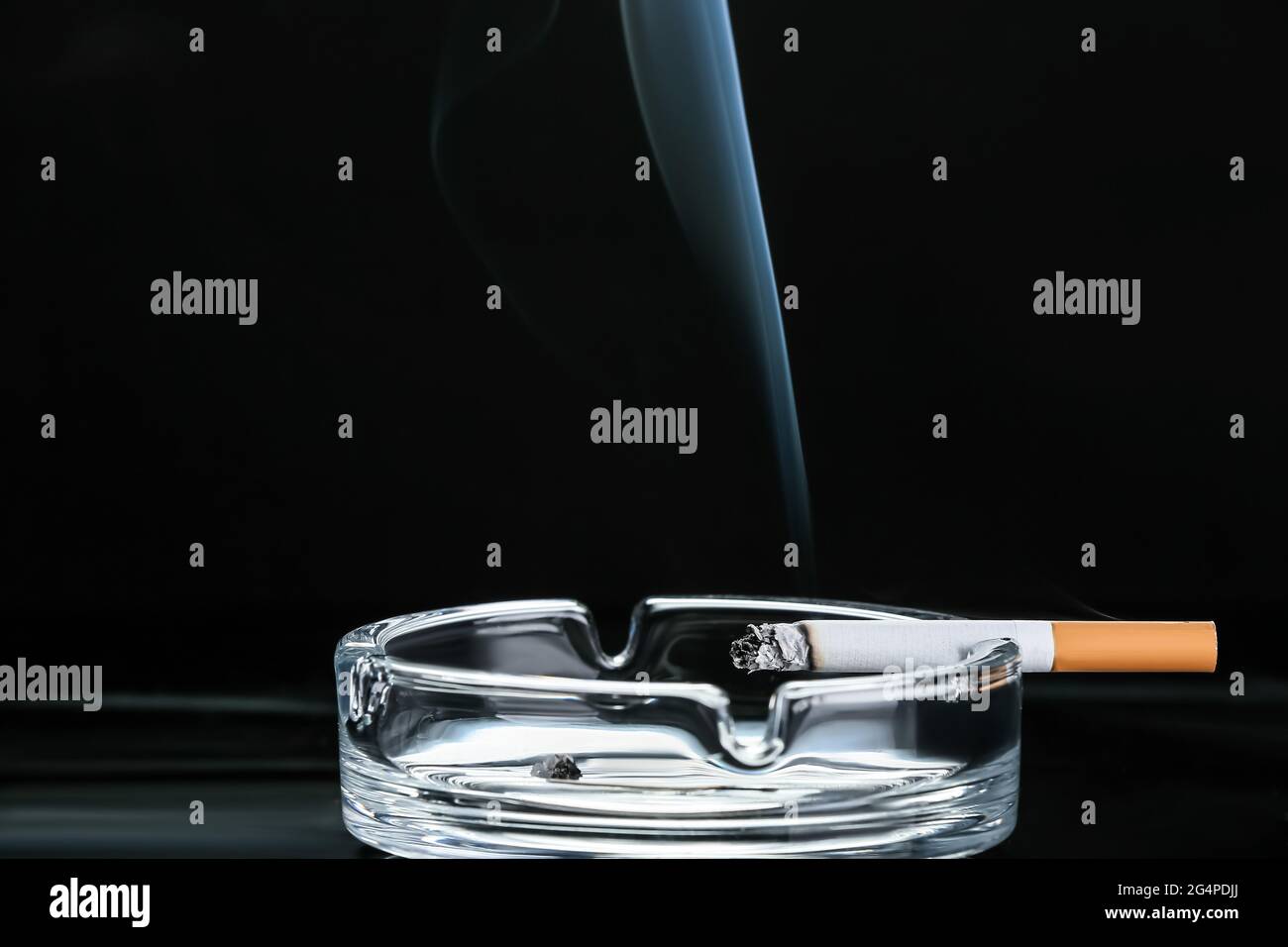 Ash tray with cigarette on dark background Stock Photo - Alamy