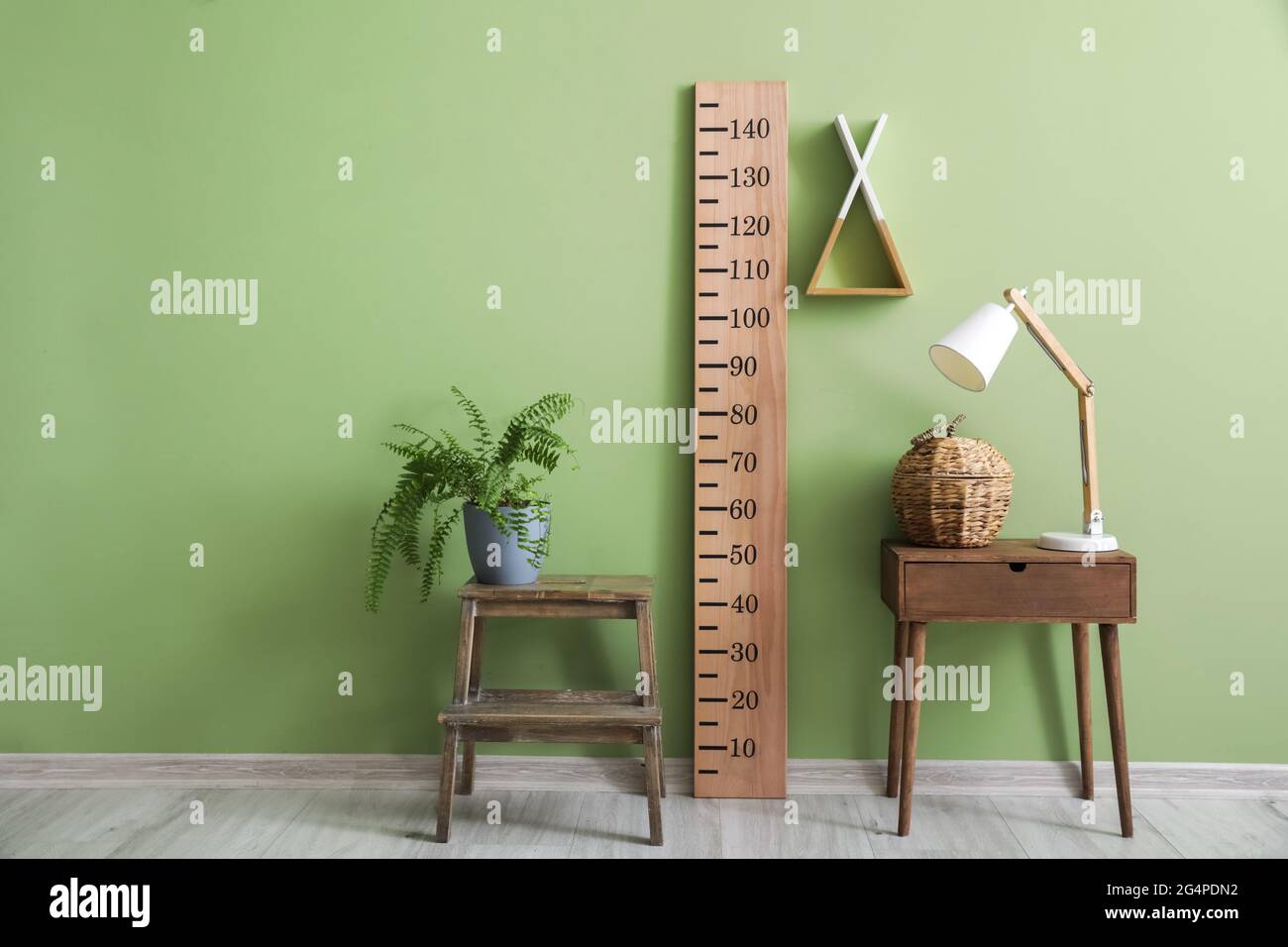 Wooden stadiometer and tables near color wall Stock Photo - Alamy