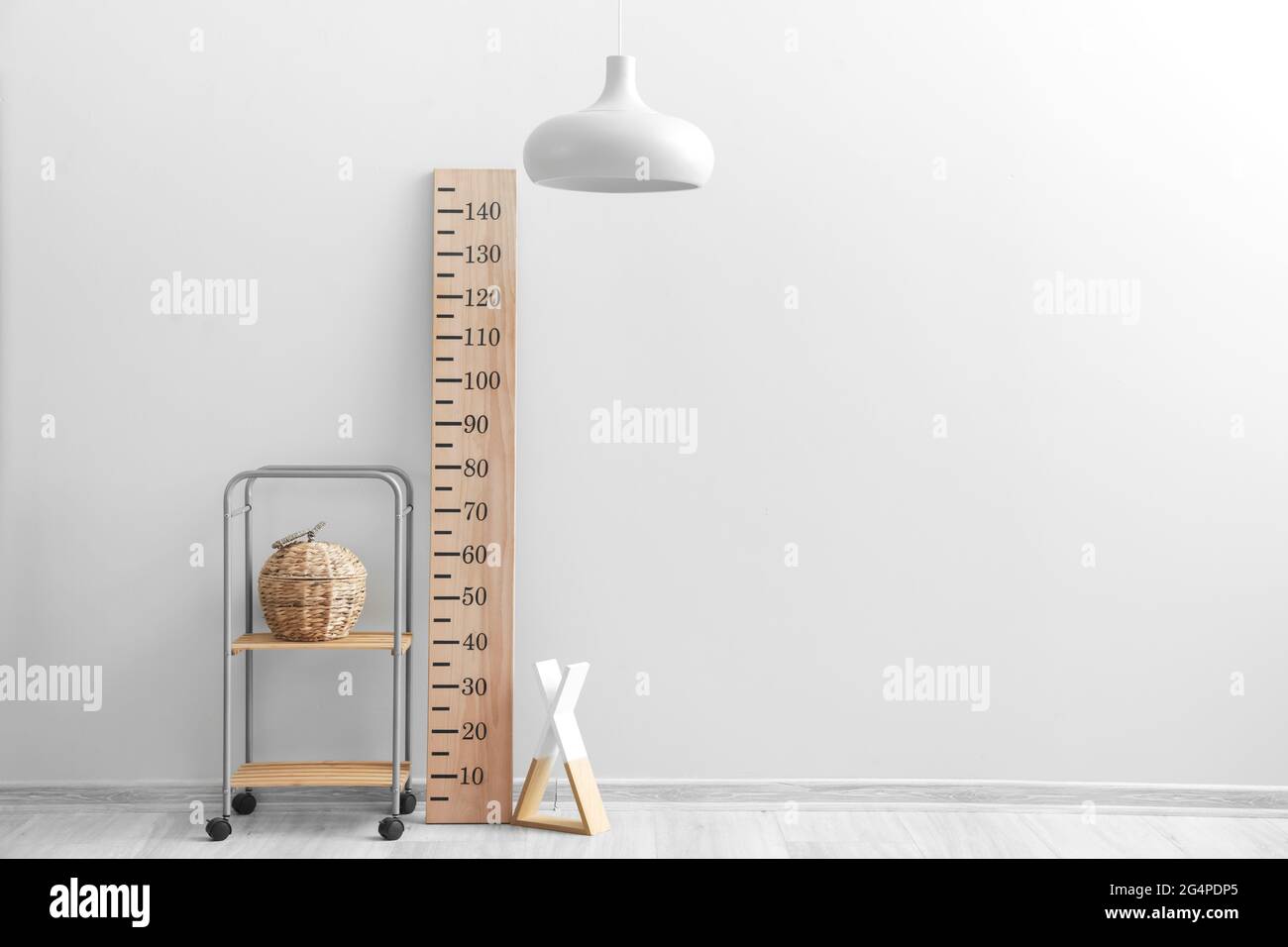 Wooden stadiometer with stand and decor near light wall Stock Photo - Alamy