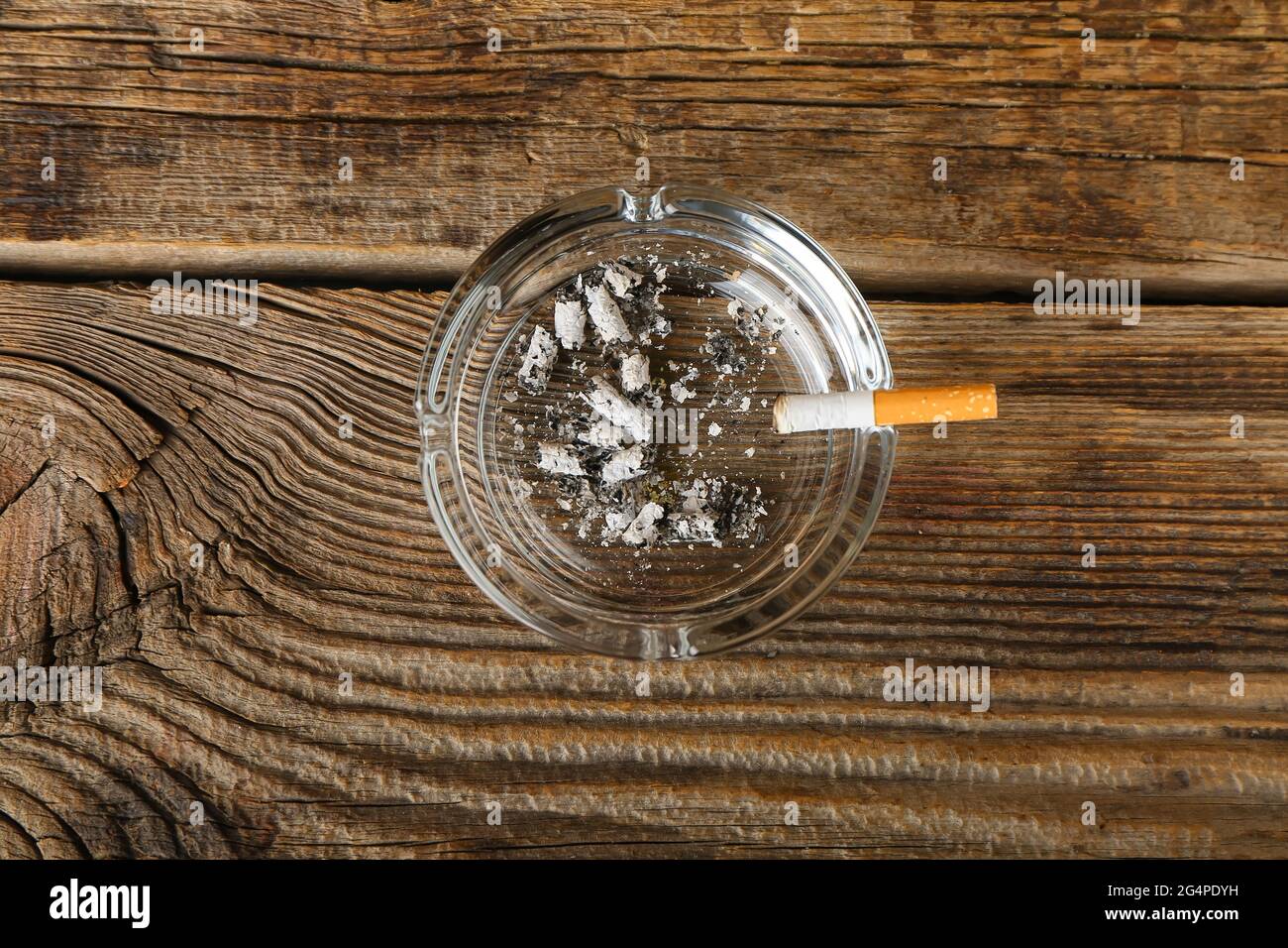Ash tray with cigarette on wooden background Stock Photo - Alamy