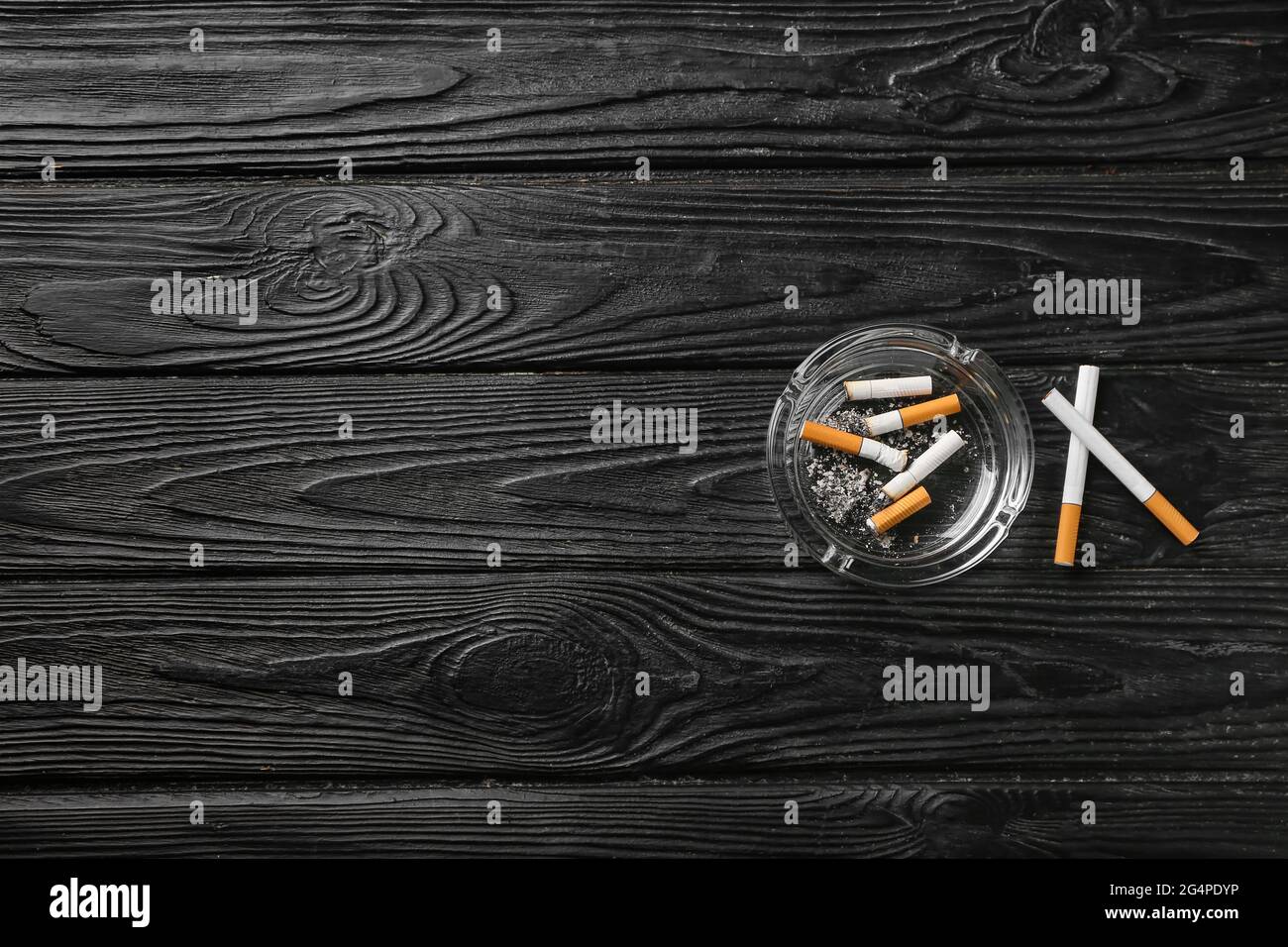 Ash tray and cigarettes on dark wooden background Stock Photo - Alamy