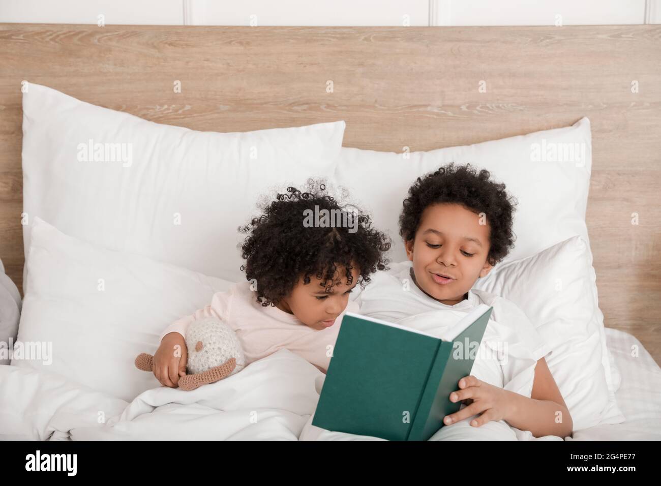 African-American children reading book in bed Stock Photo - Alamy