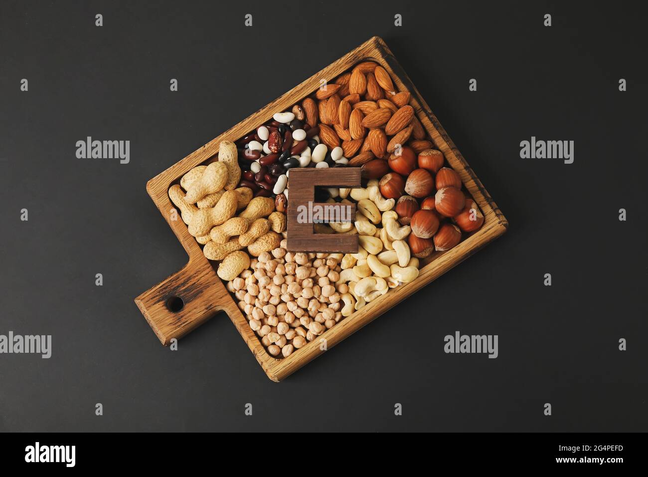 Board with different healthy nuts and beans rich in vitamin E on dark ...