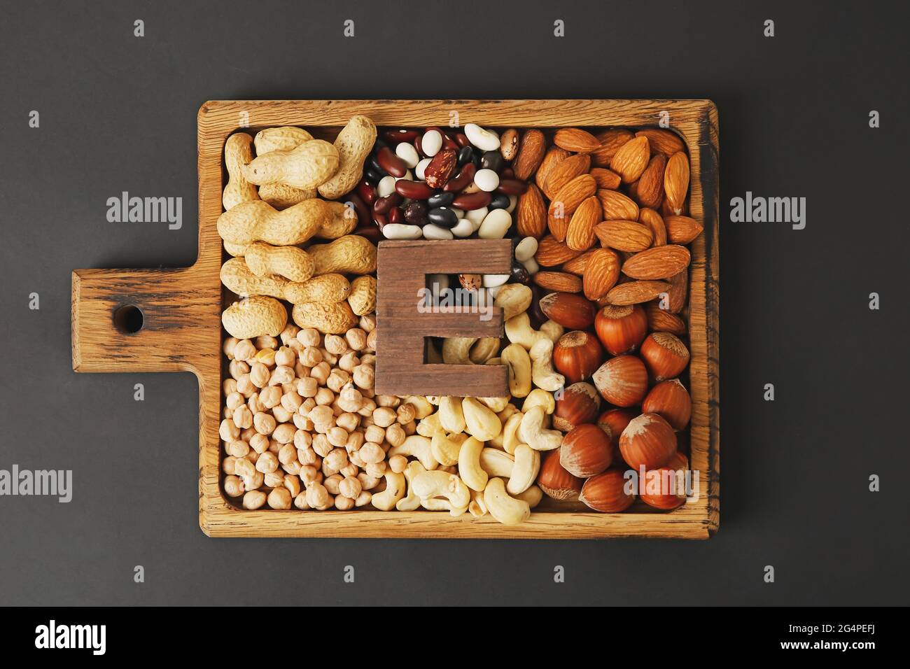 Board with different healthy nuts and beans rich in vitamin E on dark ...